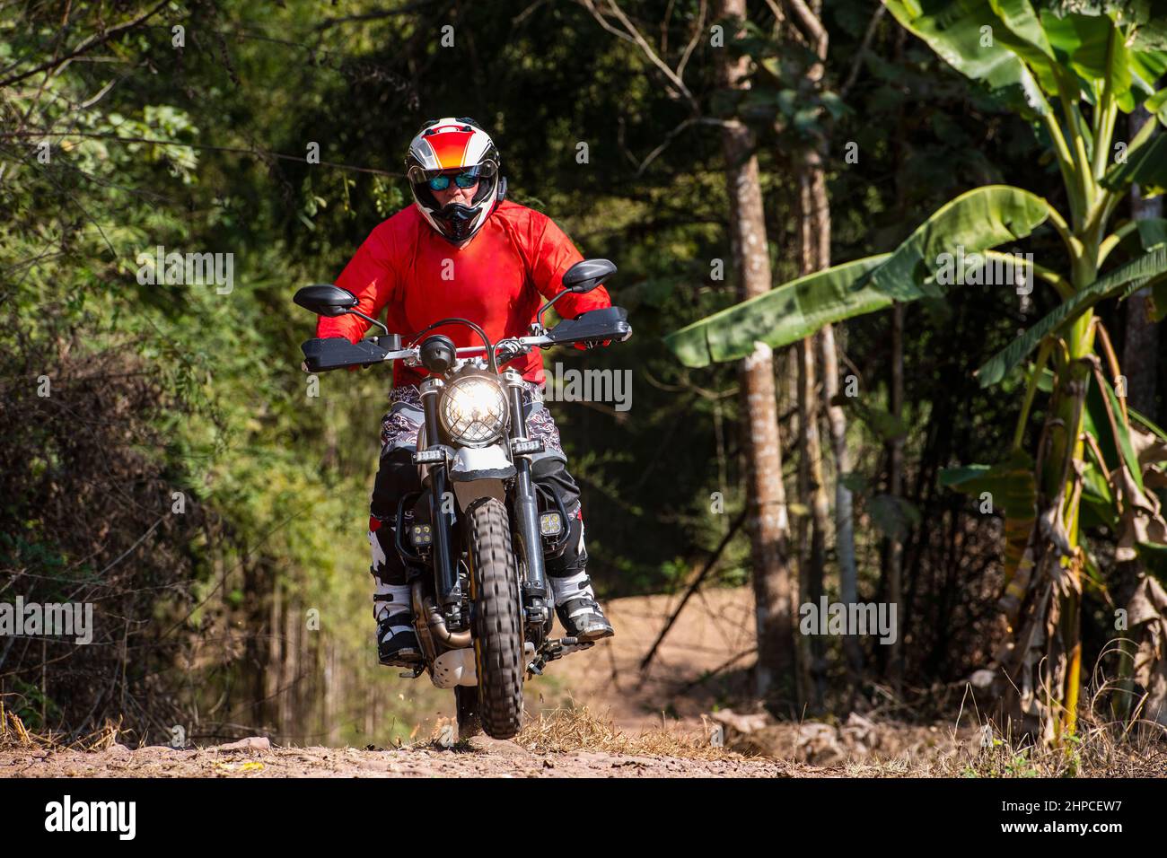 Man riding his scrambler type motorcycle on rugged terrain in Thailand ...