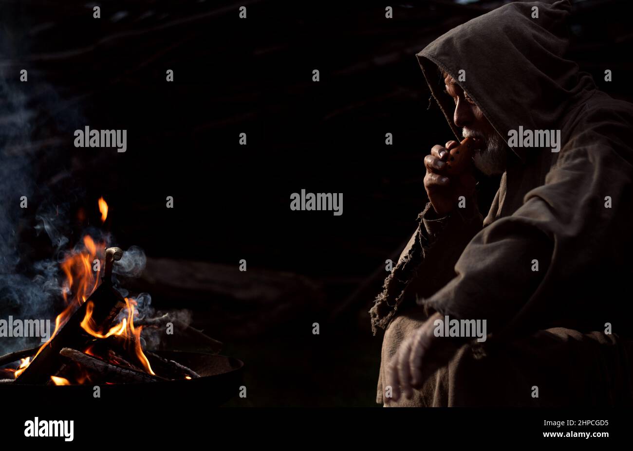 Old poor man sitting by the fire with a flute in the Middle Ages Stock ...