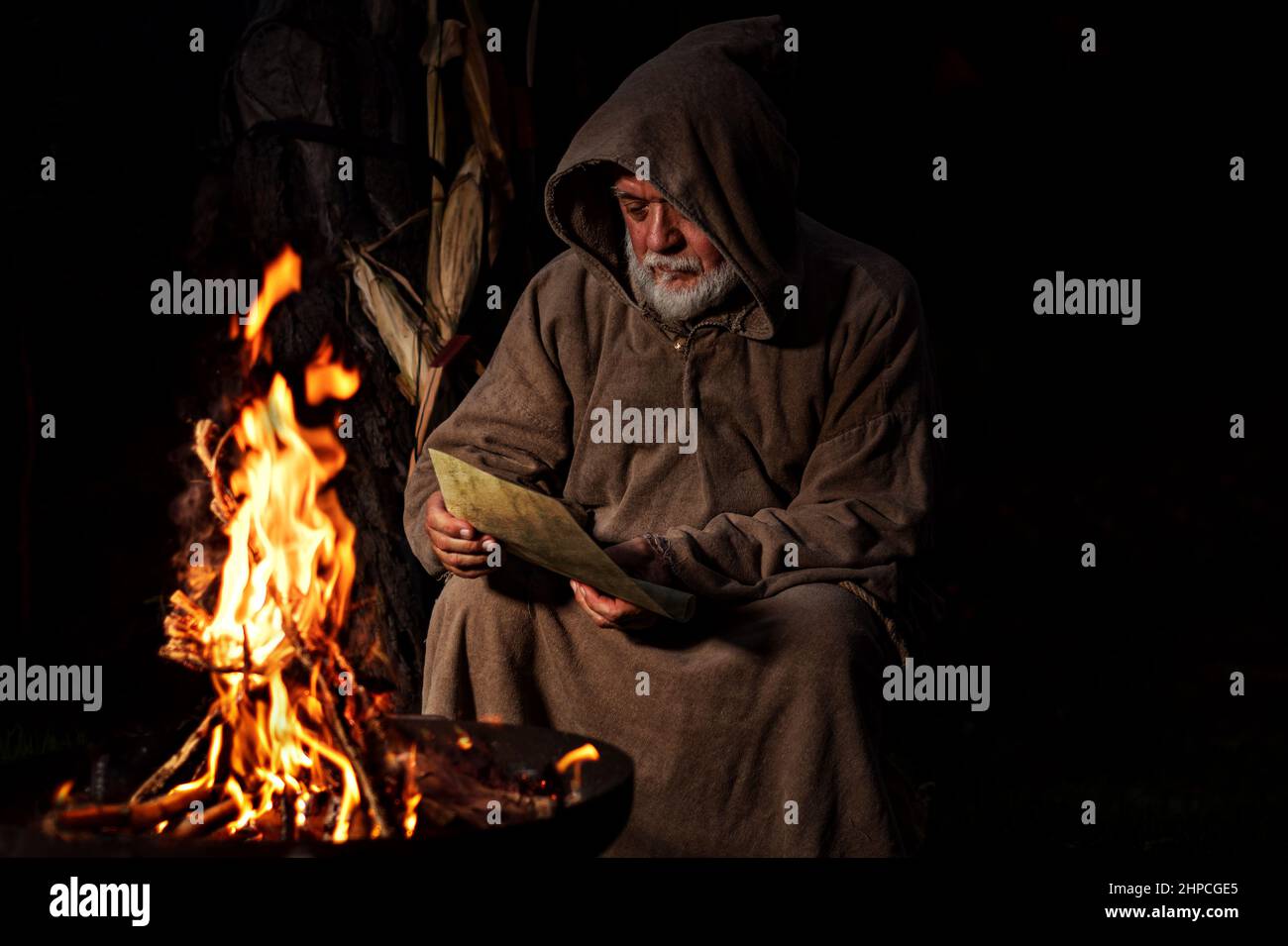 Old medieval man reading message by the fire Stock Photo - Alamy