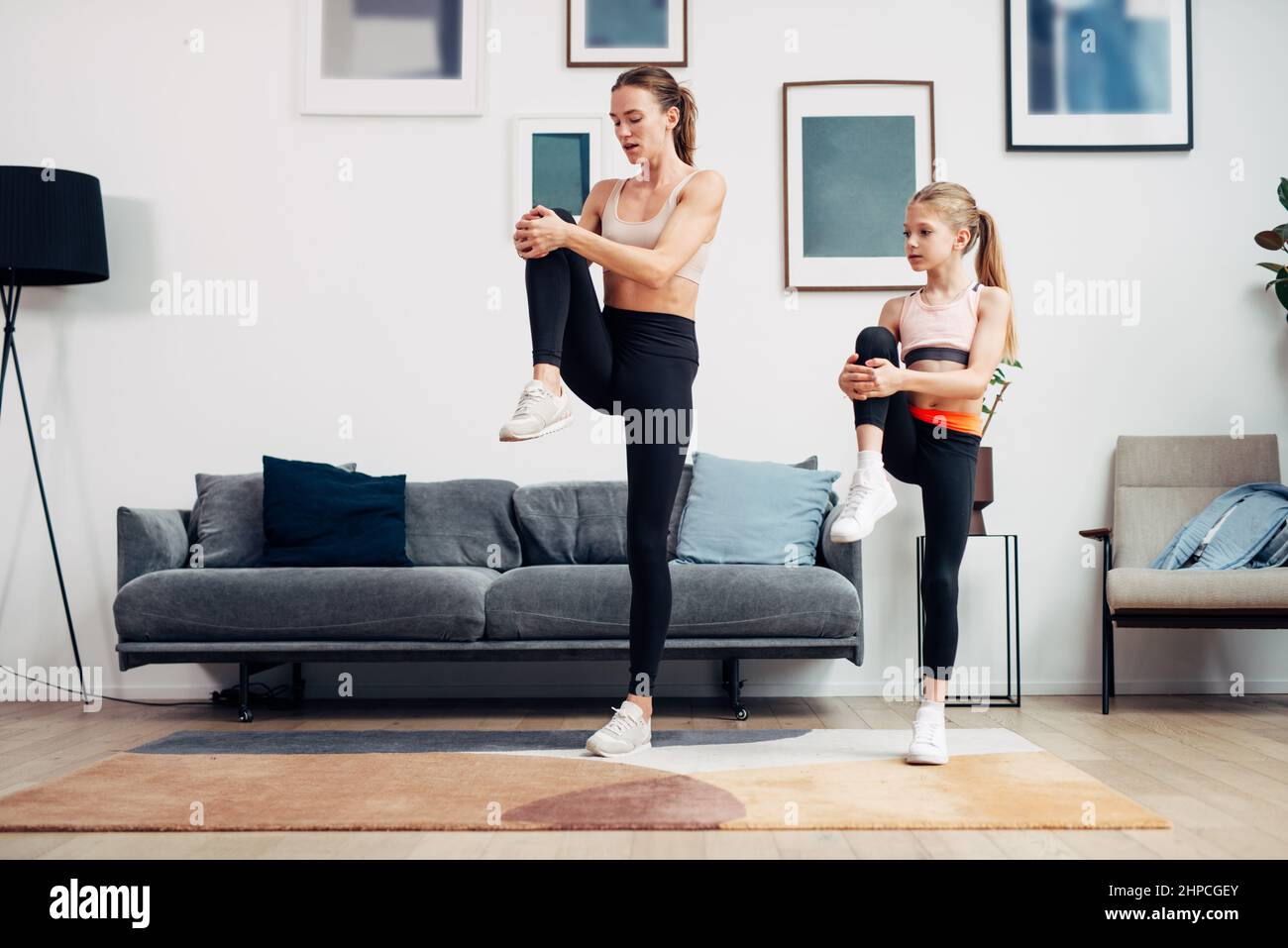 Mother and daughter working out at home, doing stretching exercises ...
