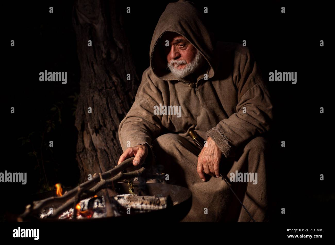Poor medieval fighter sits by the campfire at night Stock Photo - Alamy