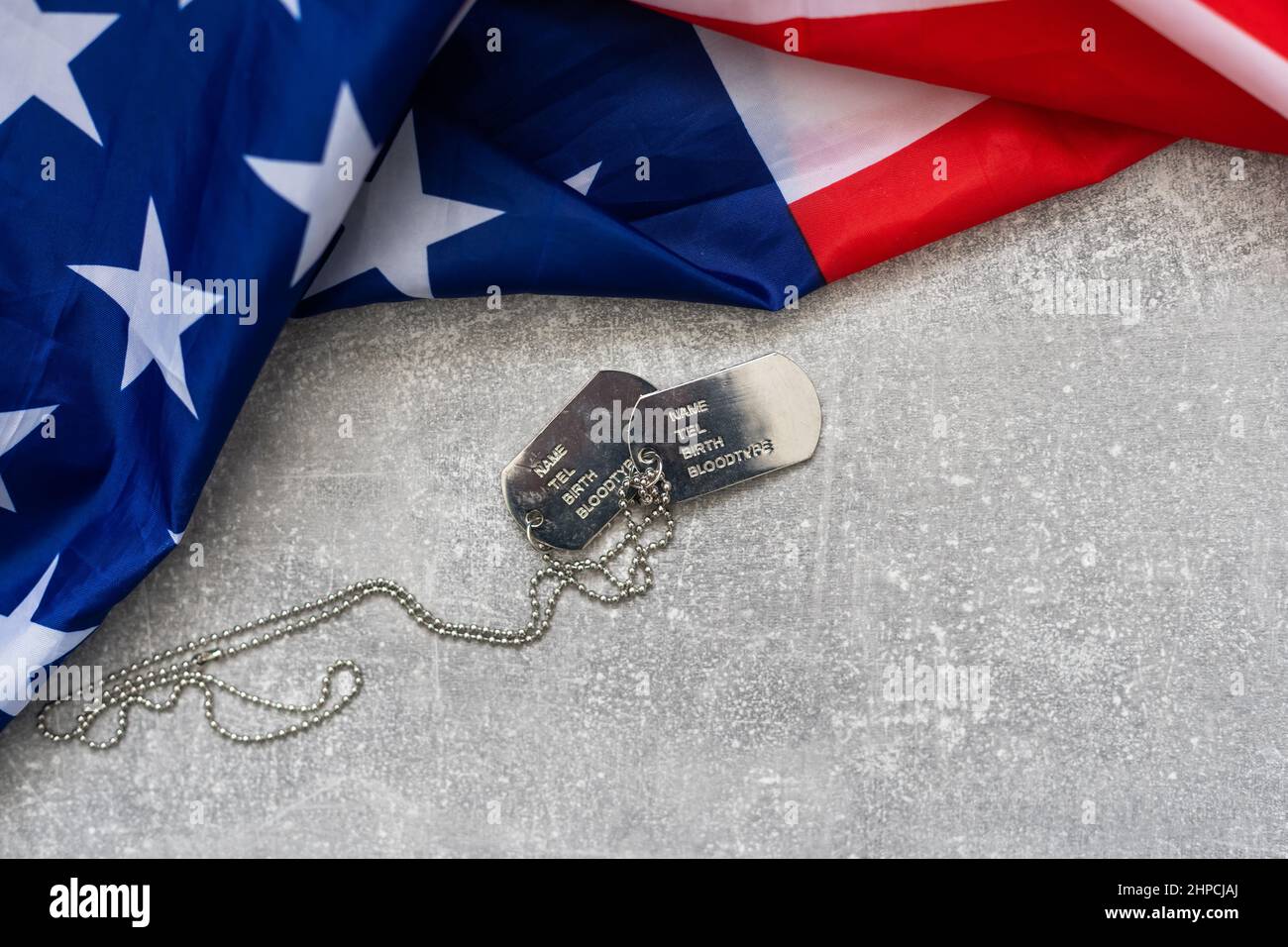 Army Dog tag token with 9mm bullets and pistol lie on folded United ...