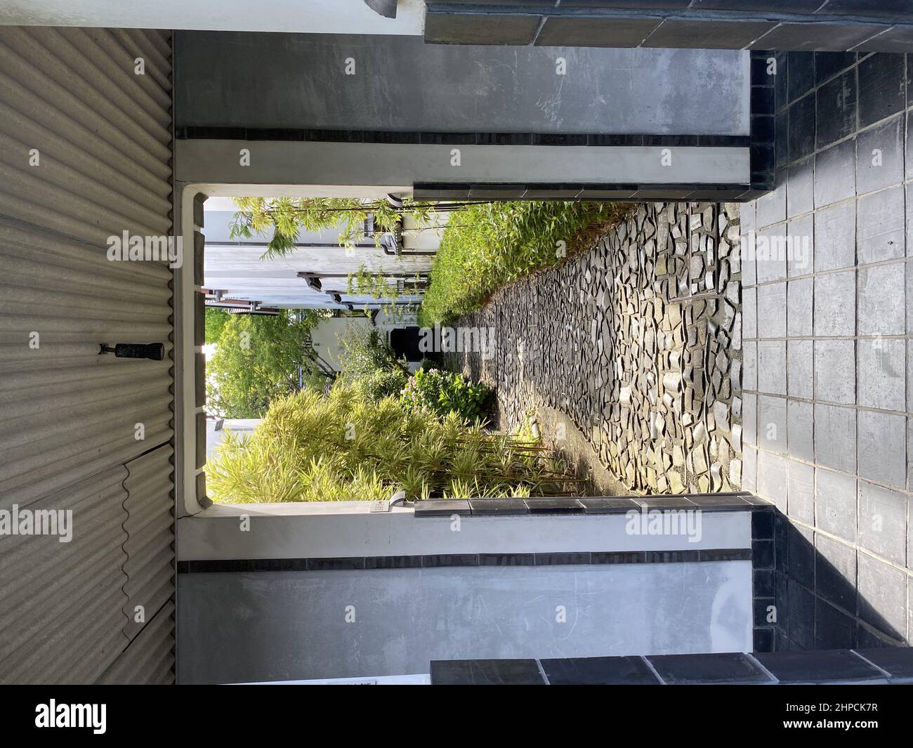 Vertical shot of an entrance opening to the garden with a paved path ...
