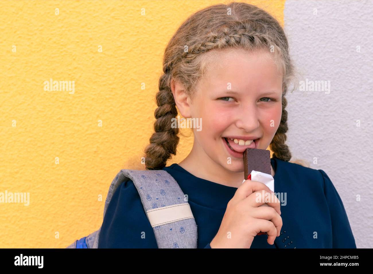 Girl eating a chocolate bar closeup. Portrait of a schoolgirl on the ...