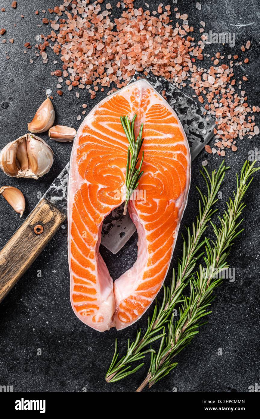 Raw Salmon trout Fish Steak on butcher table with meat cleaver. Black ...