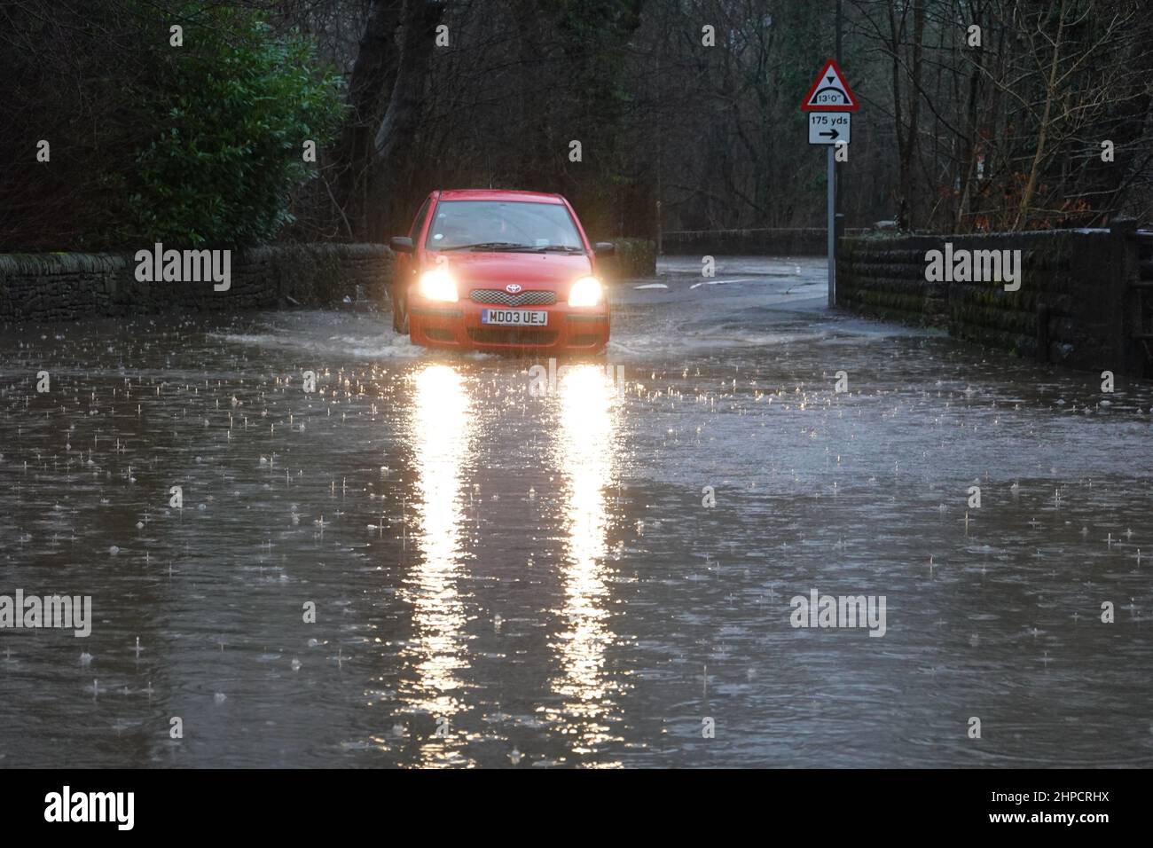 A red car drives through a flooded Bridge Street in New Mills ...