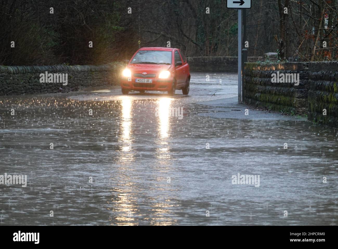 A red car drives through a flooded Bridge Street in New Mills ...