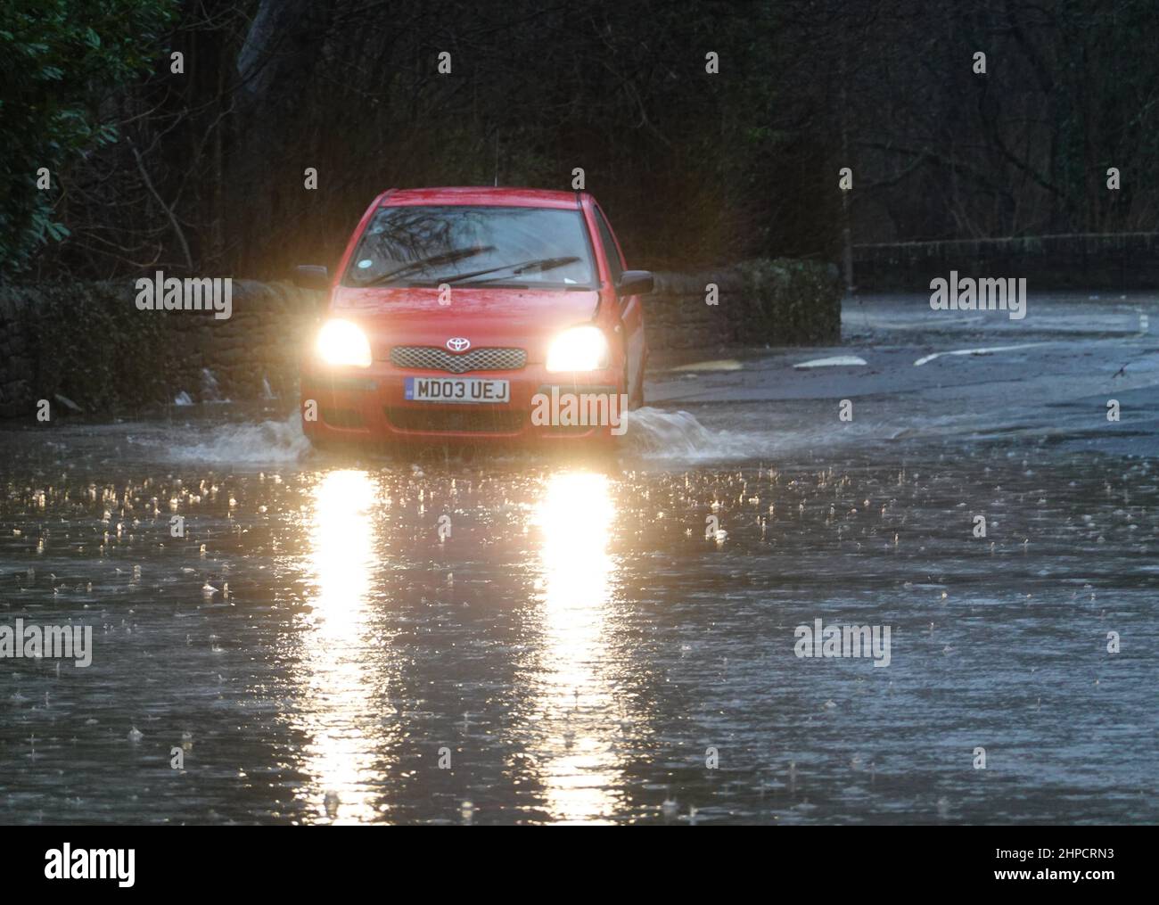 A red car drives through a flooded Bridge Street in New Mills ...