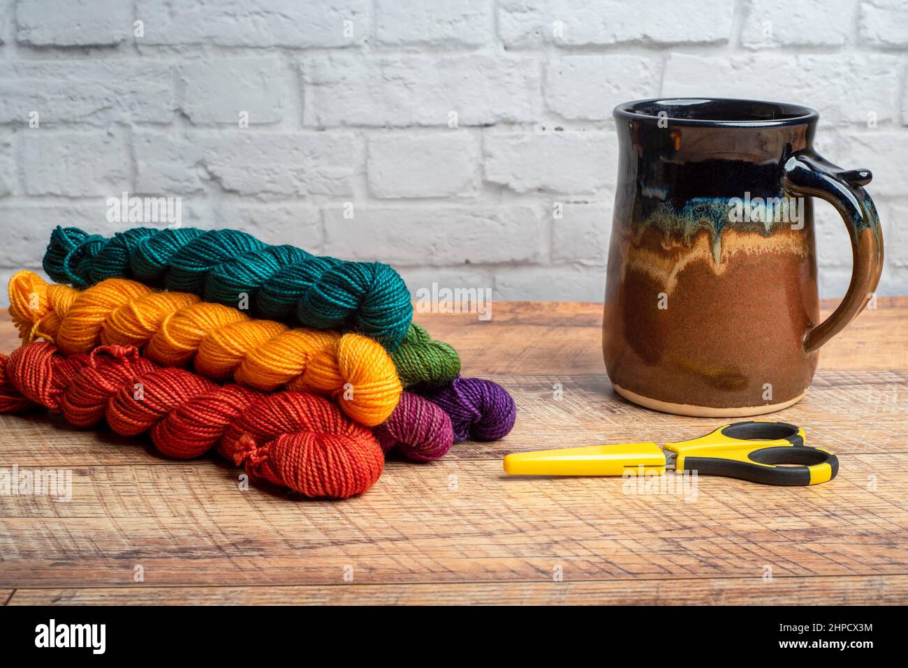 Multiple skeins of yarn on a table with scissors and coffee Stock Photo ...
