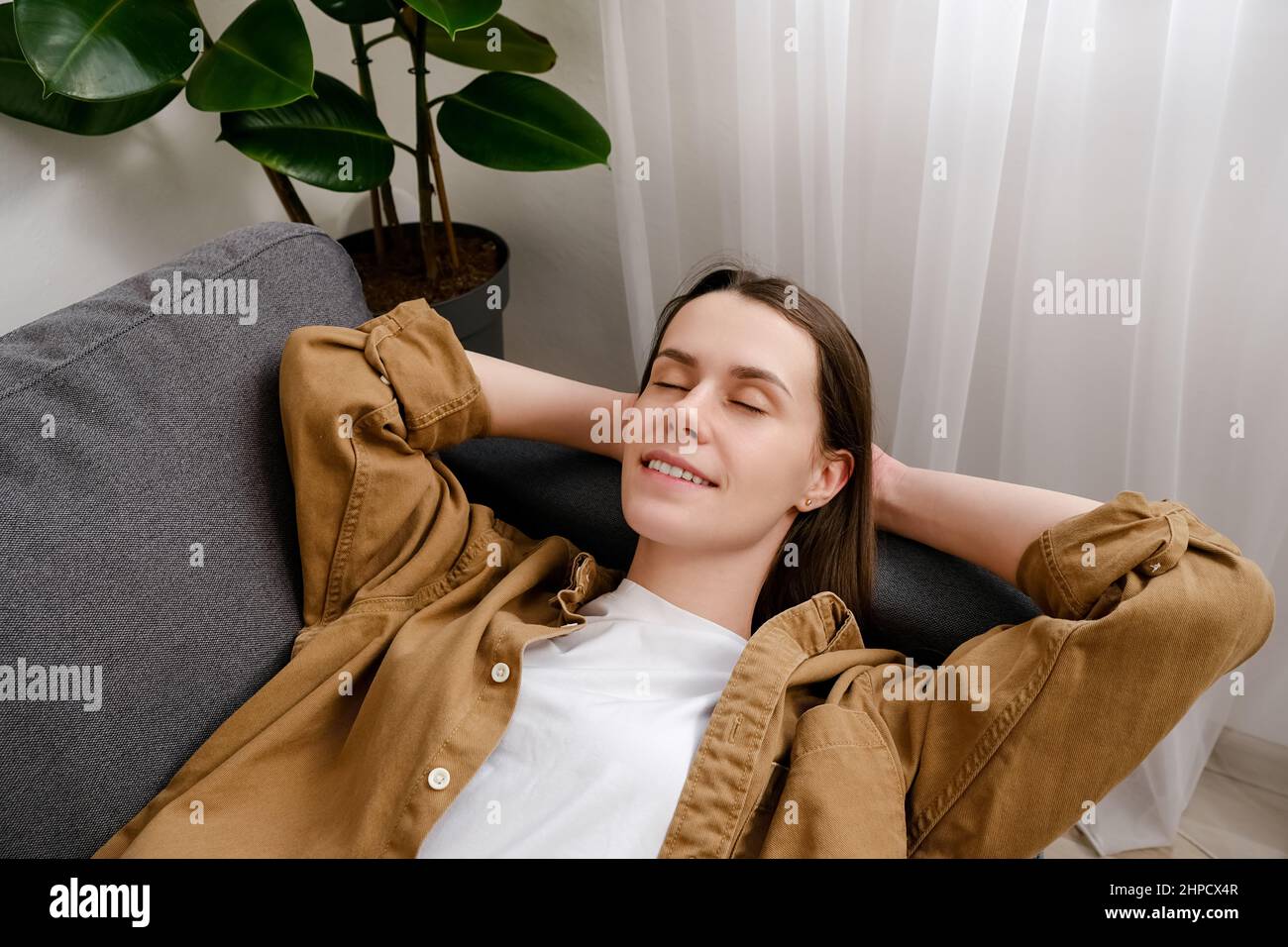 Top view of serene young brunette female resting on couch taking deep ...