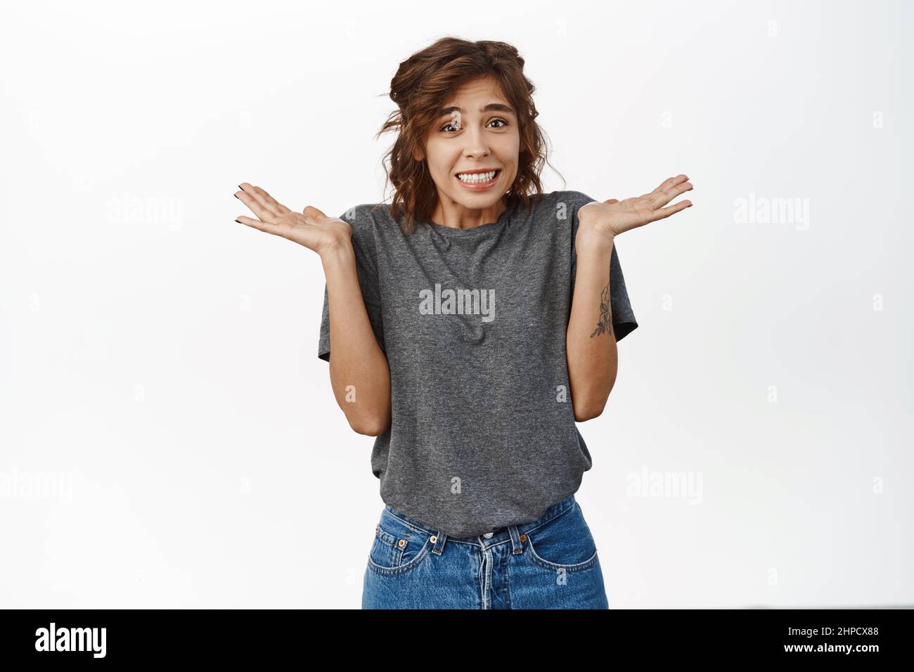 Cute smiling girl shrugging shoulders clueless and awkward, dont know ...