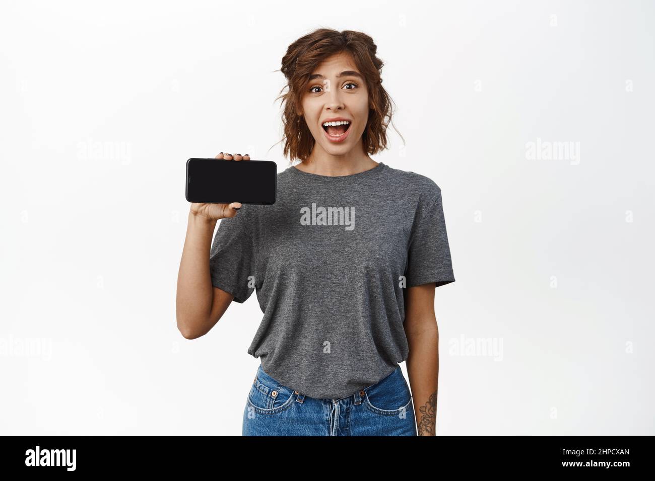 Happy smiling girl shows horizontal phone screen, mobile app interface ...