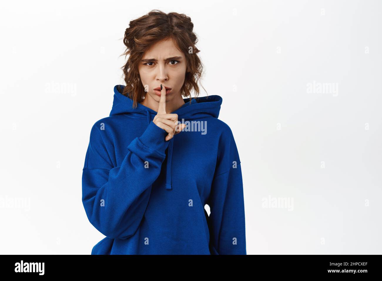 Angry bossy girl shushing, press finger at lips and hush, shh be quiet ...