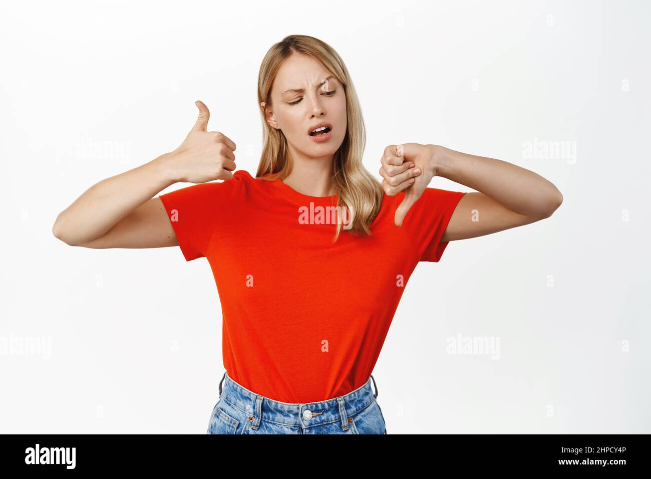 Weighing decision. Young indecisive girl makes choice, shows thumbs up ...