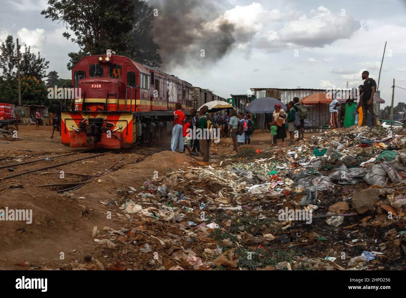Residents wait as a train approaches it's makeshift station in Kibera ...