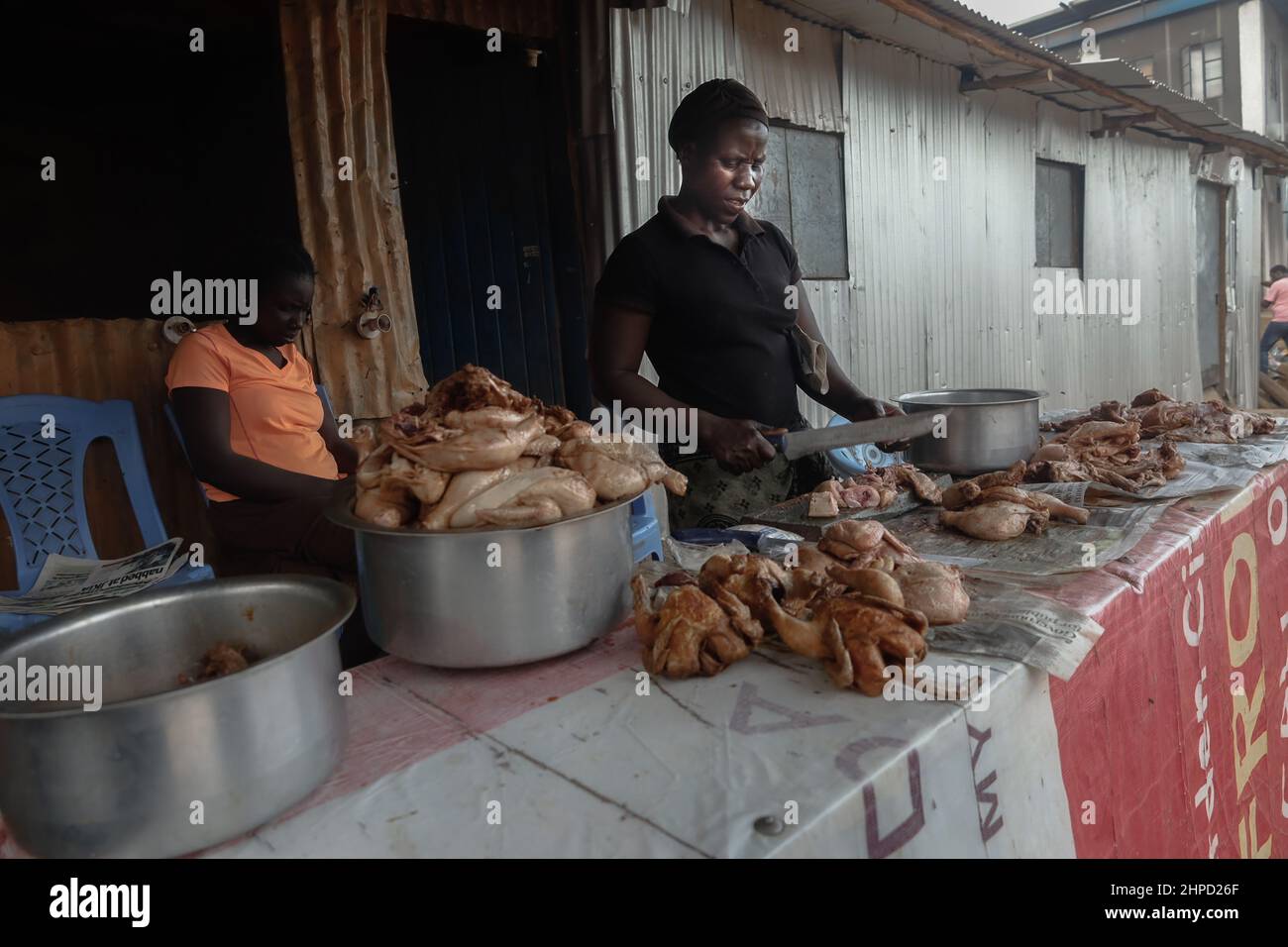 A woman sells fried chicken by the streets in Kibera Slums. Inside ...
