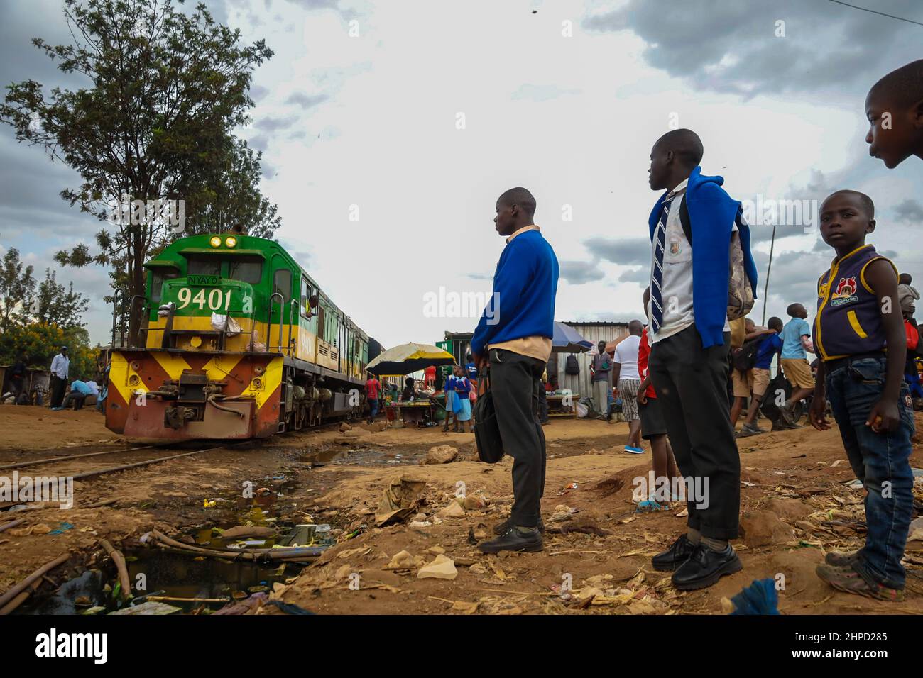Students wait as a train approaches it's makeshift station in Kibera ...