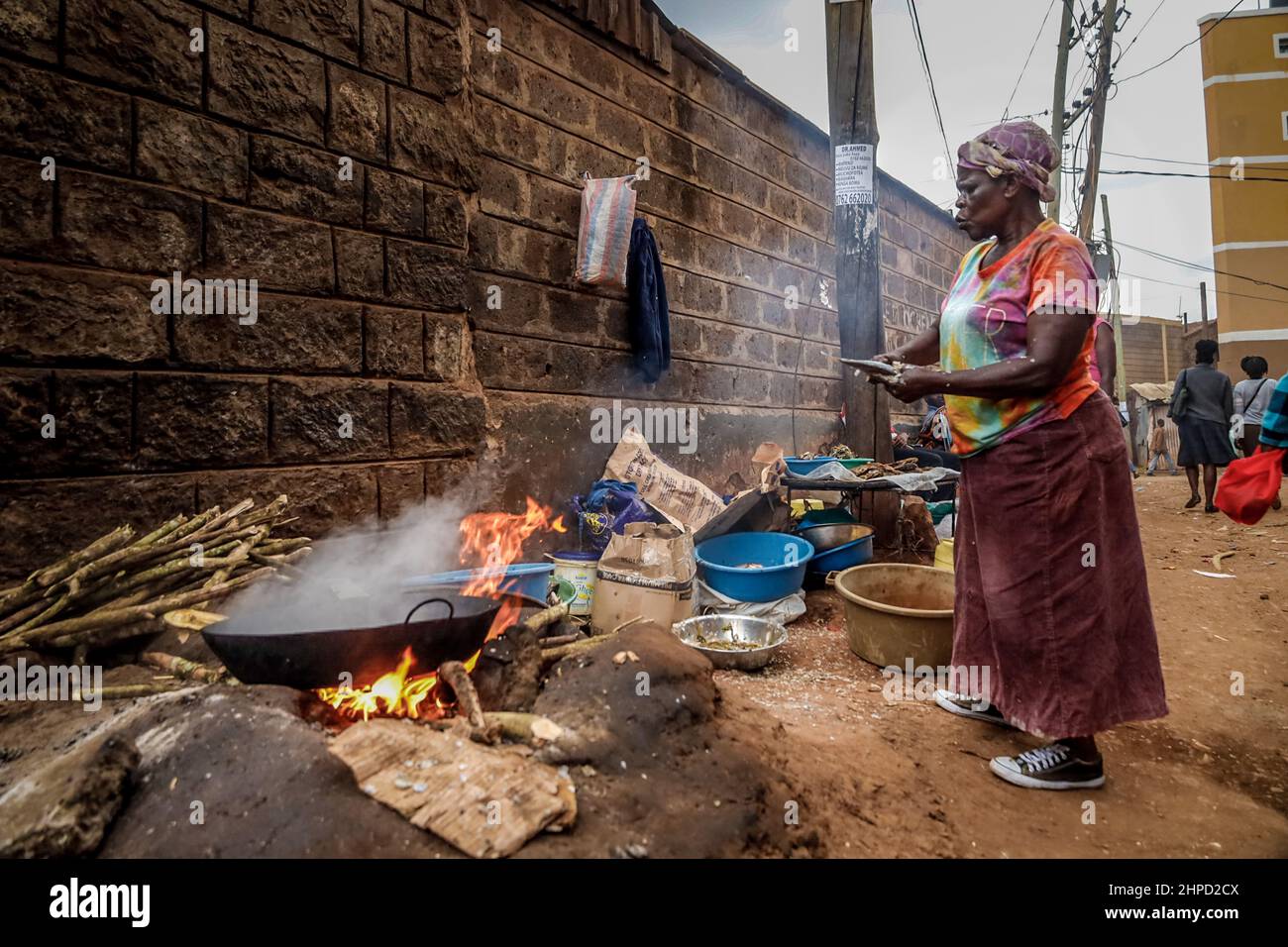 A woman prepares fish for sale by the streets in Kibera Slums. Inside ...