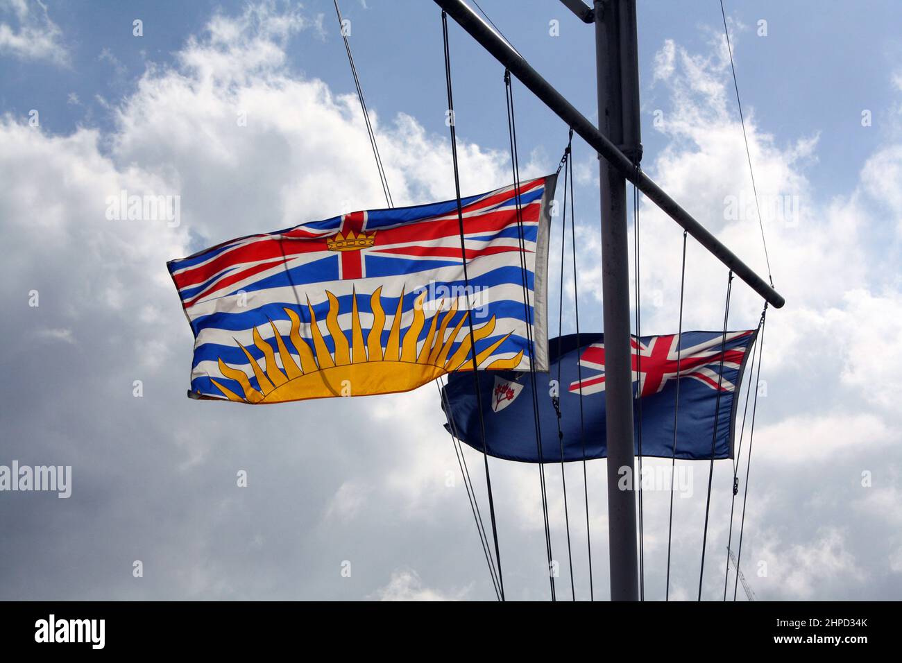 Closeup of the flags of British Columbia in wind under a cloudy sky ...