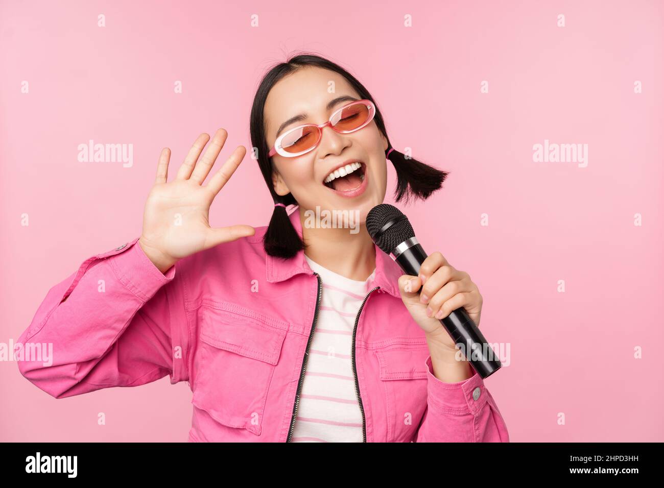 Happy beautiful asian girl singing with mic, using microphone, enjoying ...