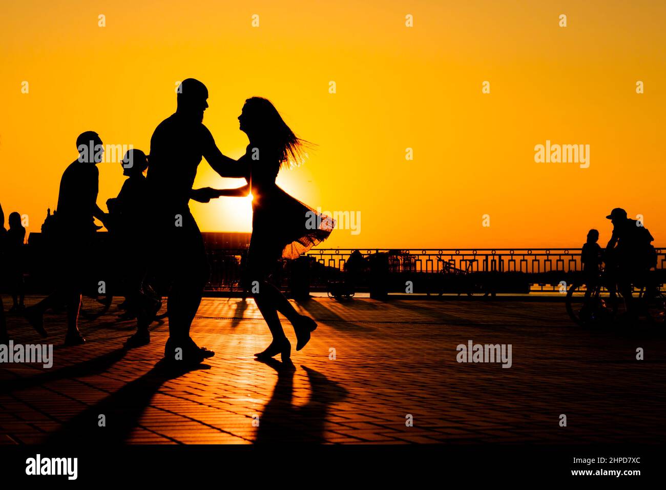 Woman and man couple silhouettes dancing against warm sunset orange sky ...