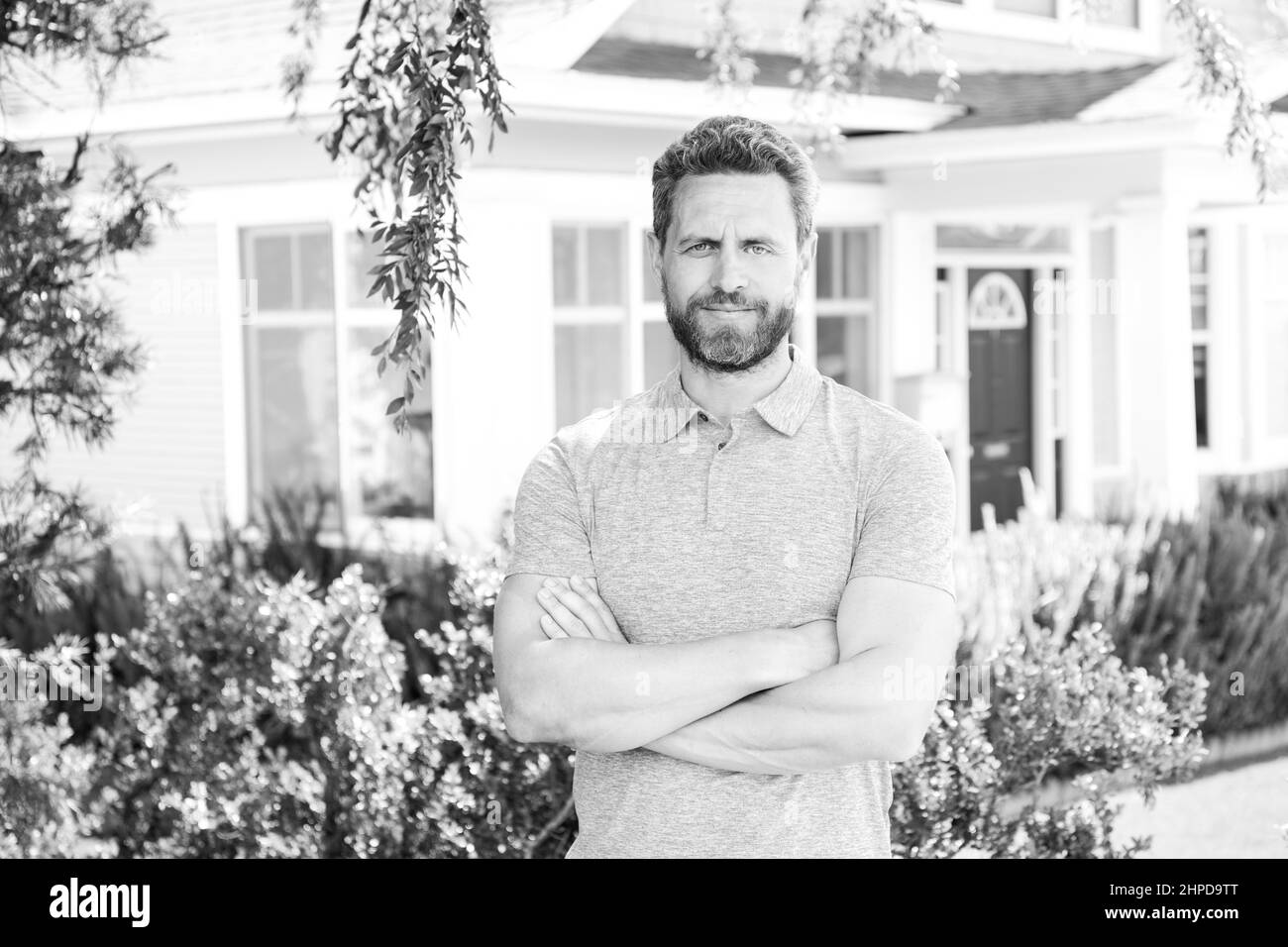 Portrait of confident real estate agent standing outside a house for ...