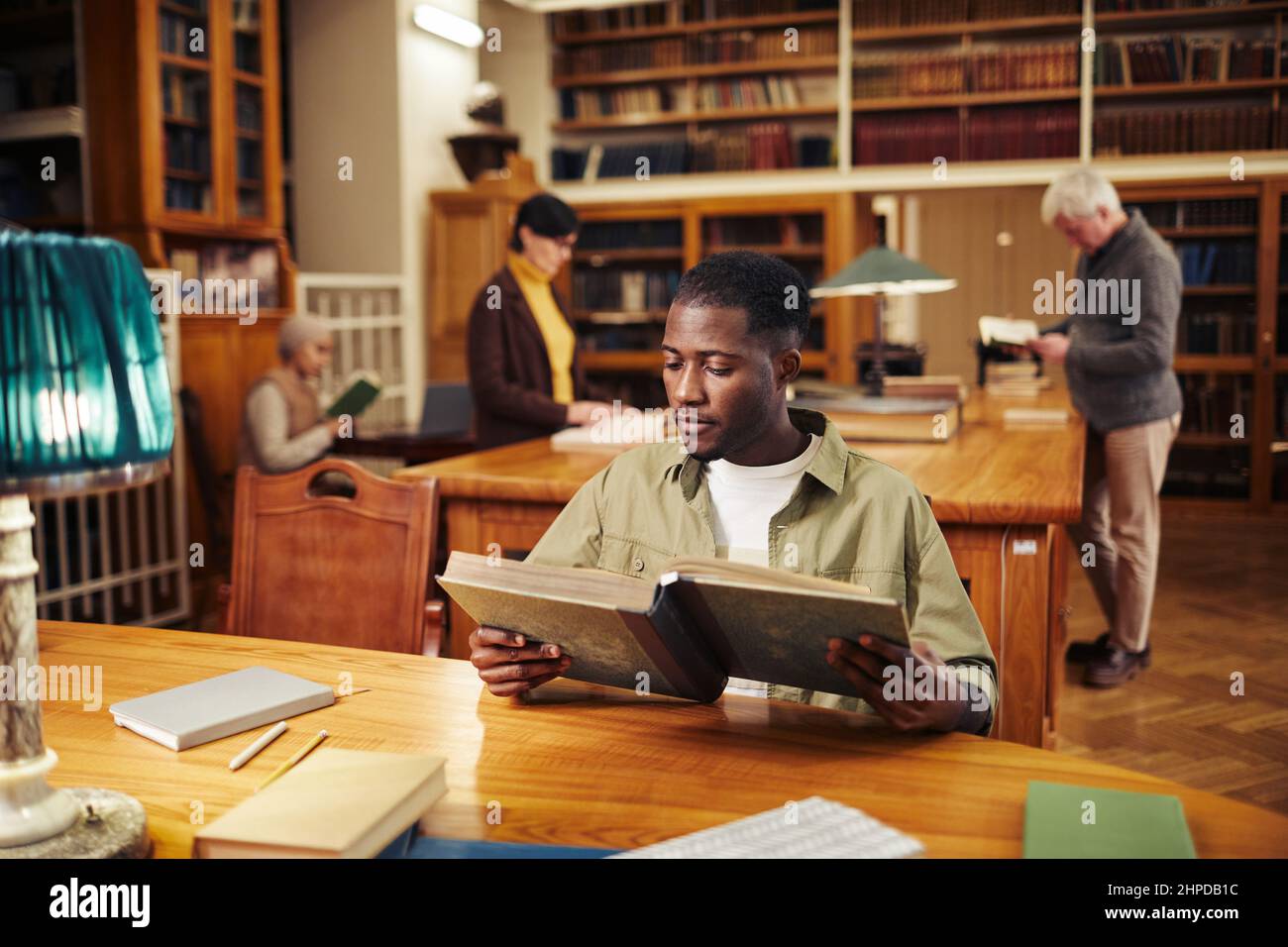 Portrait of young African-American man reading book in classic college ...