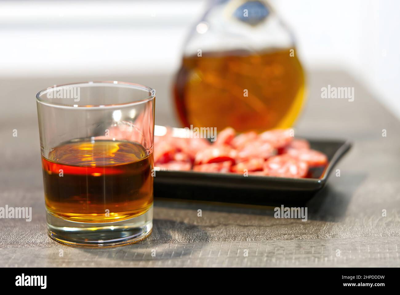 Glass of whiskey with buttle and snack on black plate Stock Photo - Alamy