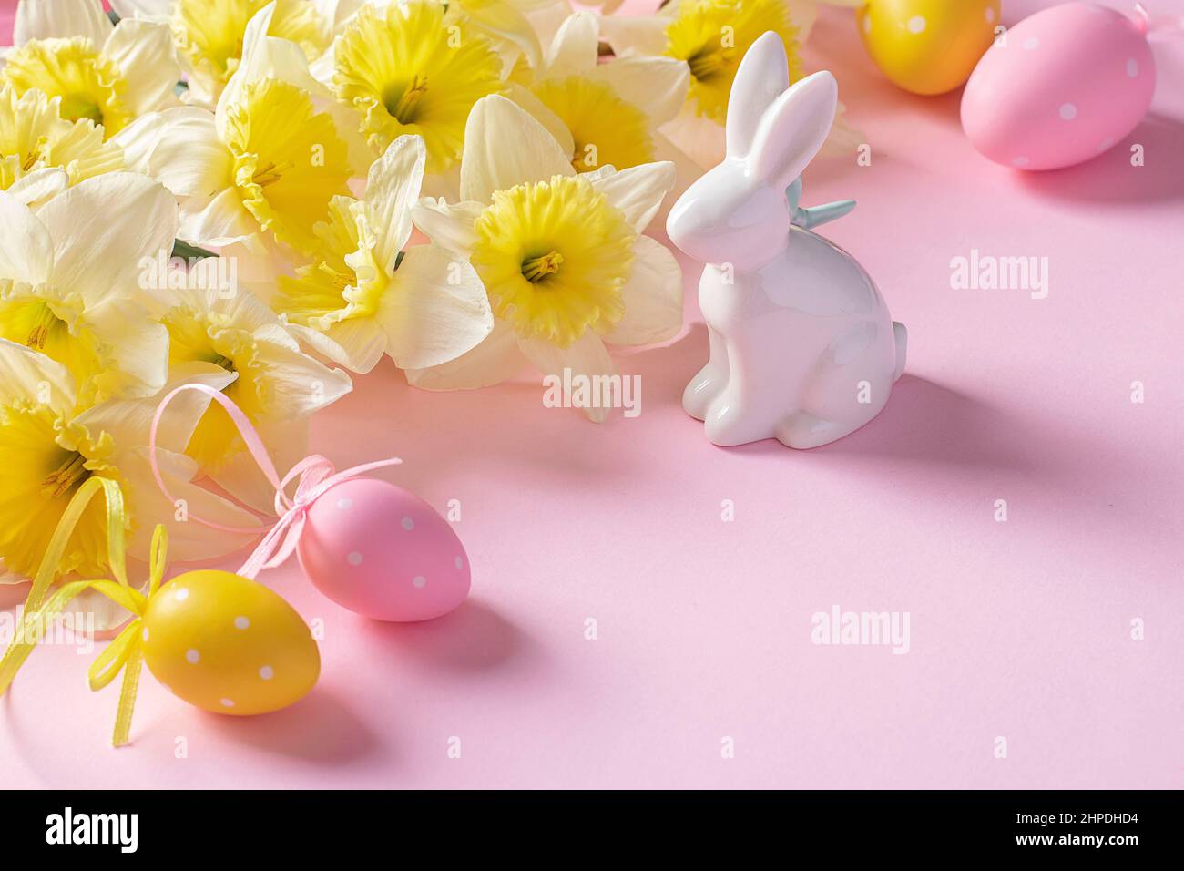 Easter bunny, daffodils, pink and yellow eggs on a pink background ...