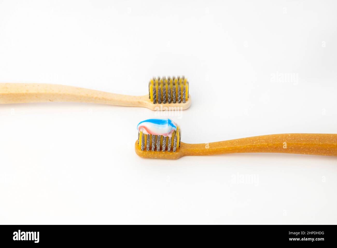 Two ceramic toothbrushes, on one of them applied colored toothpaste, on ...