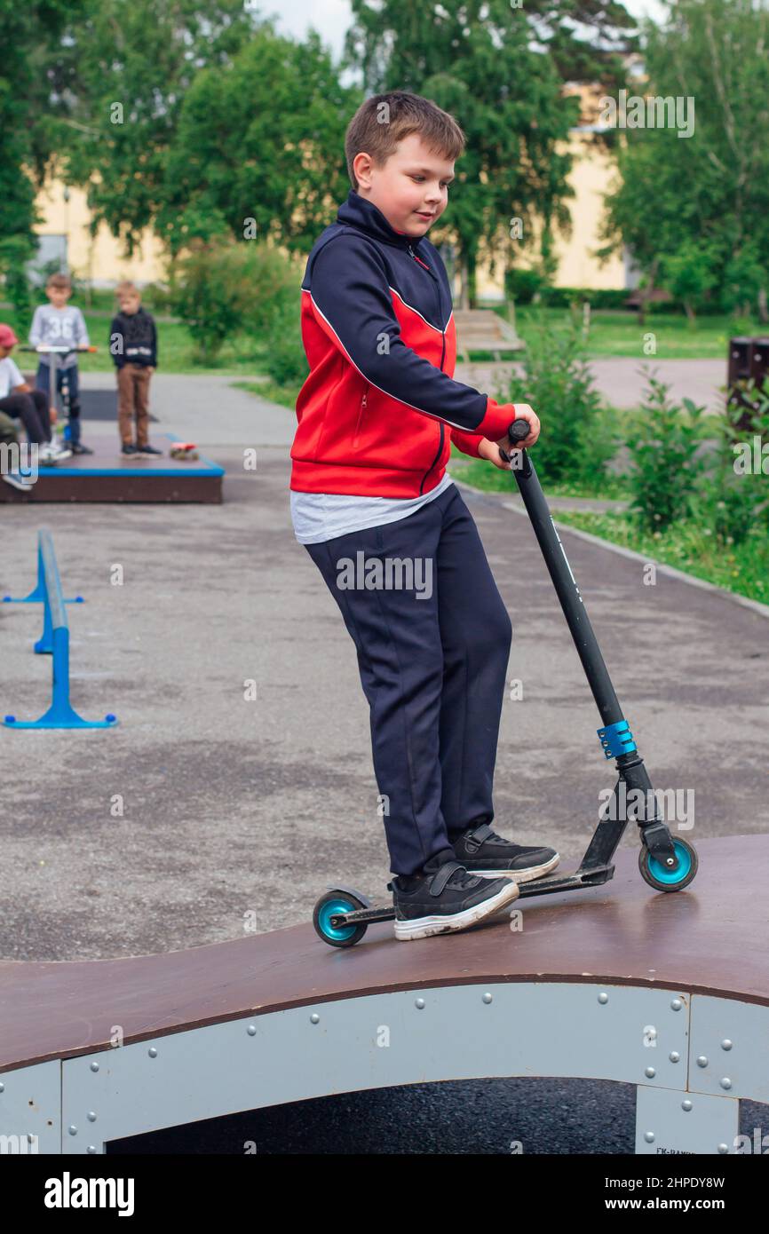 Cute boy riding scooter in a summer park. Happy teenager riding a ...