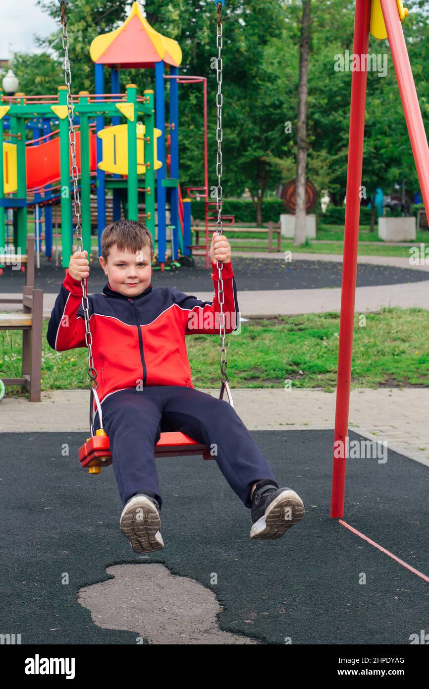 Outdoors portrait of a cute boy swinging on a swing at the playground in a park Stock Photo - Alamy