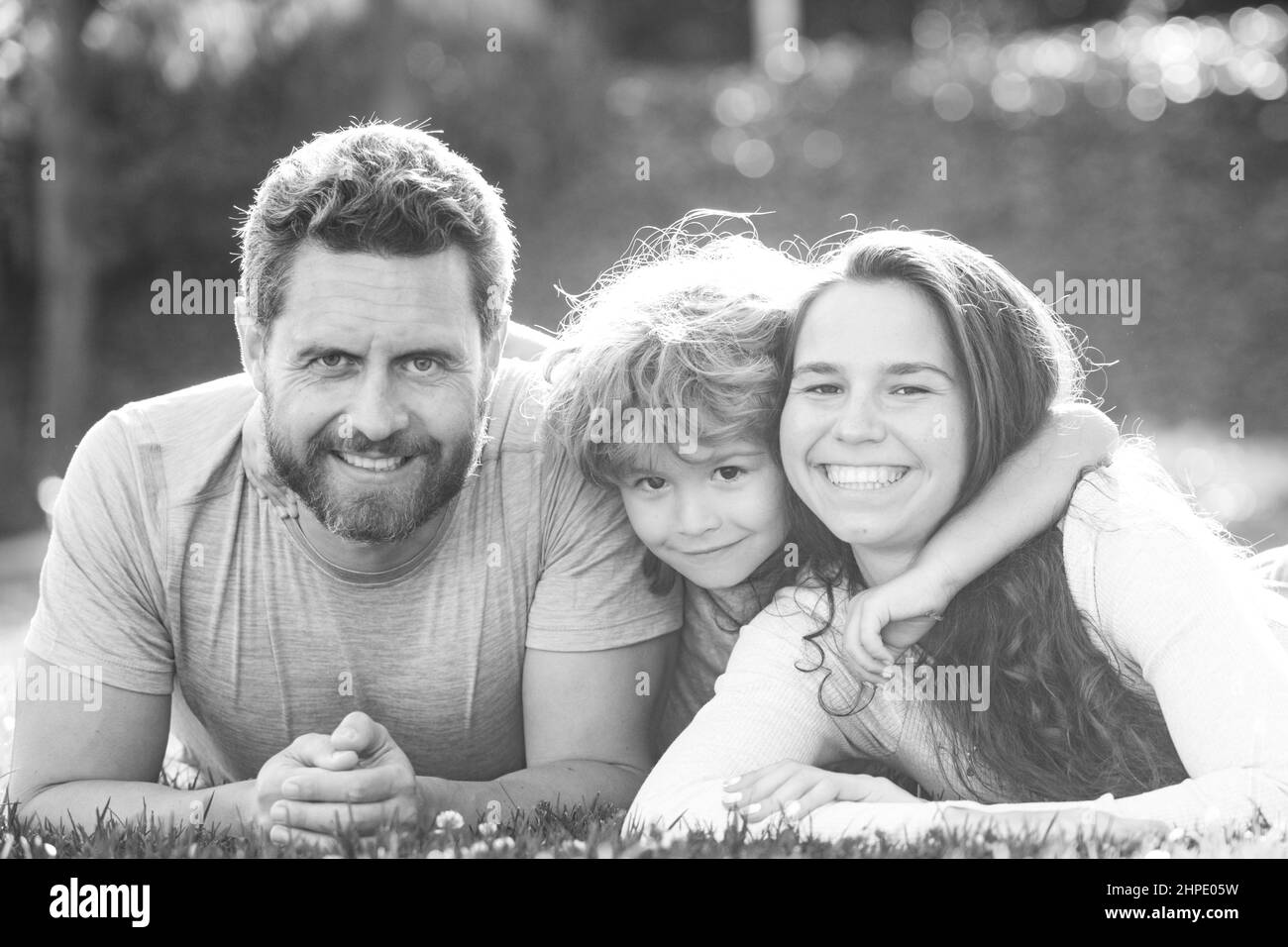 Cute family portrait hugging and embracing. Family lying on grass in ...