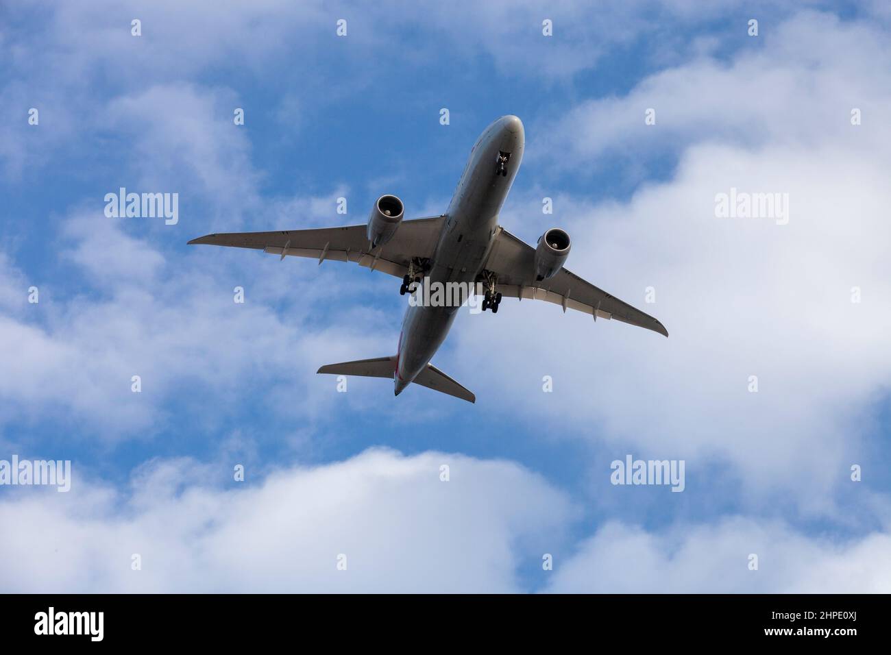 Airplane flying under clouds in the daytime Stock Photo - Alamy
