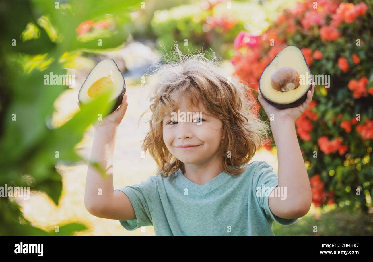 Kid eating and enjoying an avocado on a nature background. Healthy food ...