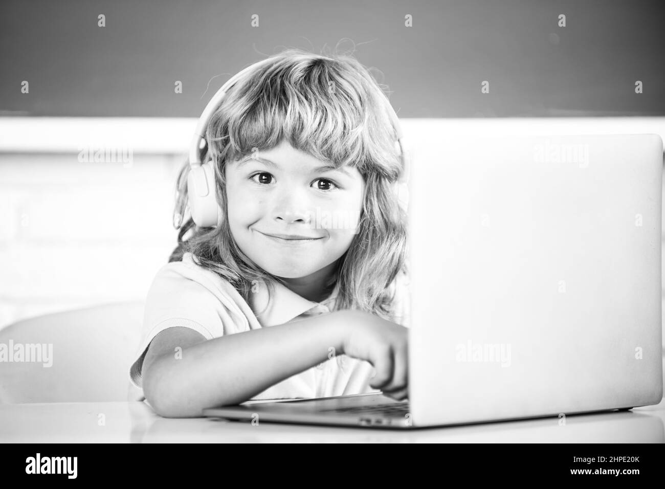 Funny school kid boy with laptop computer and headphones in class at ...