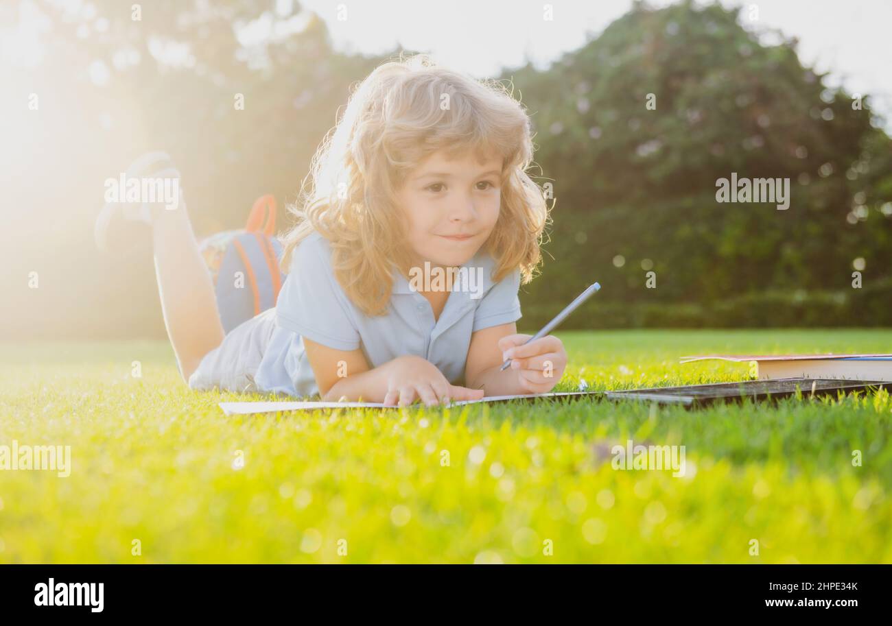Cute boy writing notes in copybook on green grass Stock Photo - Alamy