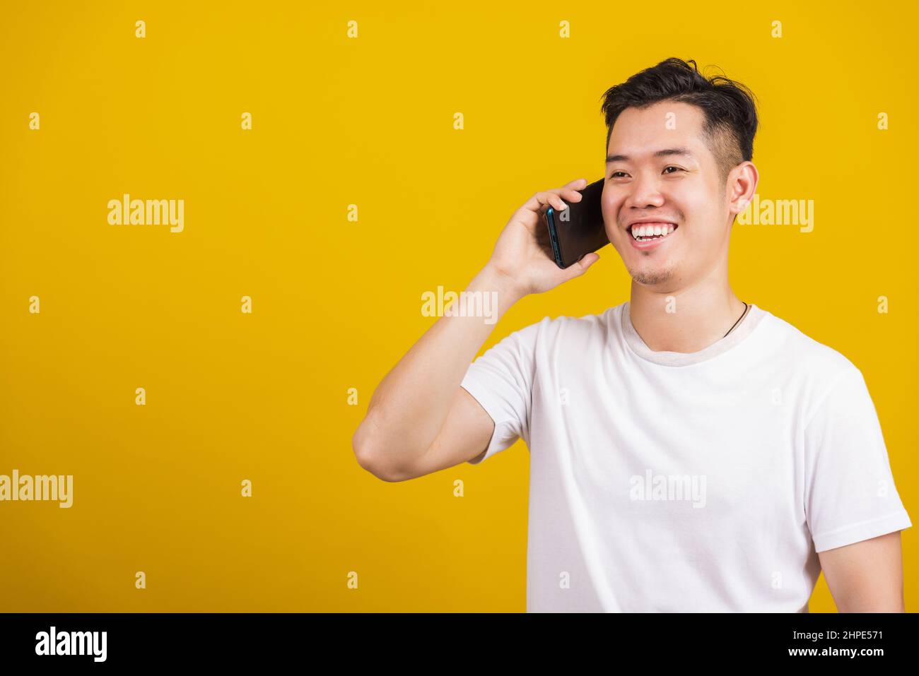Asian handsome young man smiling positive talking on cellphone ...