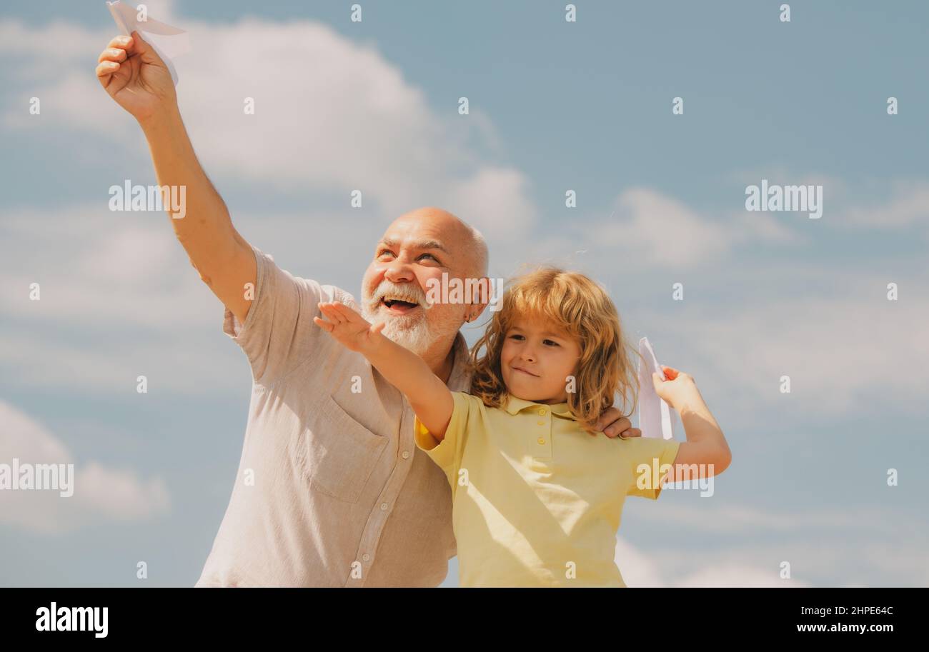 Grandfather and grandson with paper plane over blue sky and clouds. Men ...