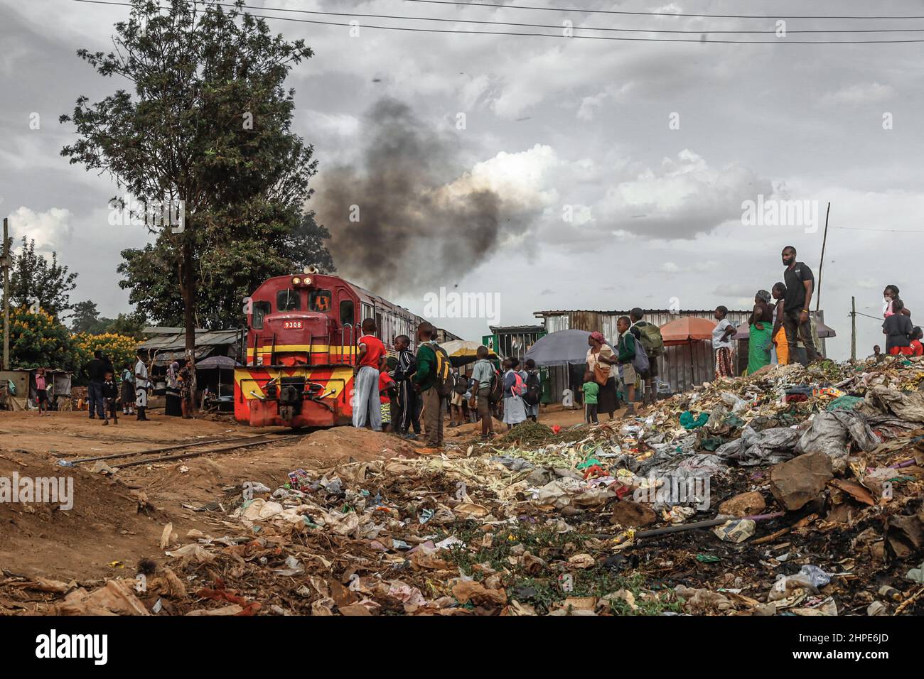 Residents wait as a train approaches it's makeshift station in Kibera ...