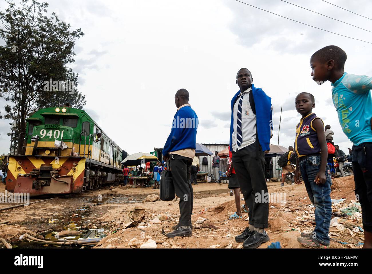 Students wait as a train approaches it's makeshift station in Kibera ...