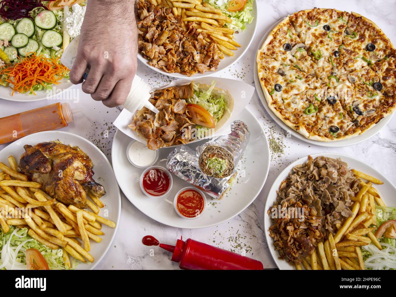 Top view of a person hand pouring sauce on dishes, durum, kebab, and ...