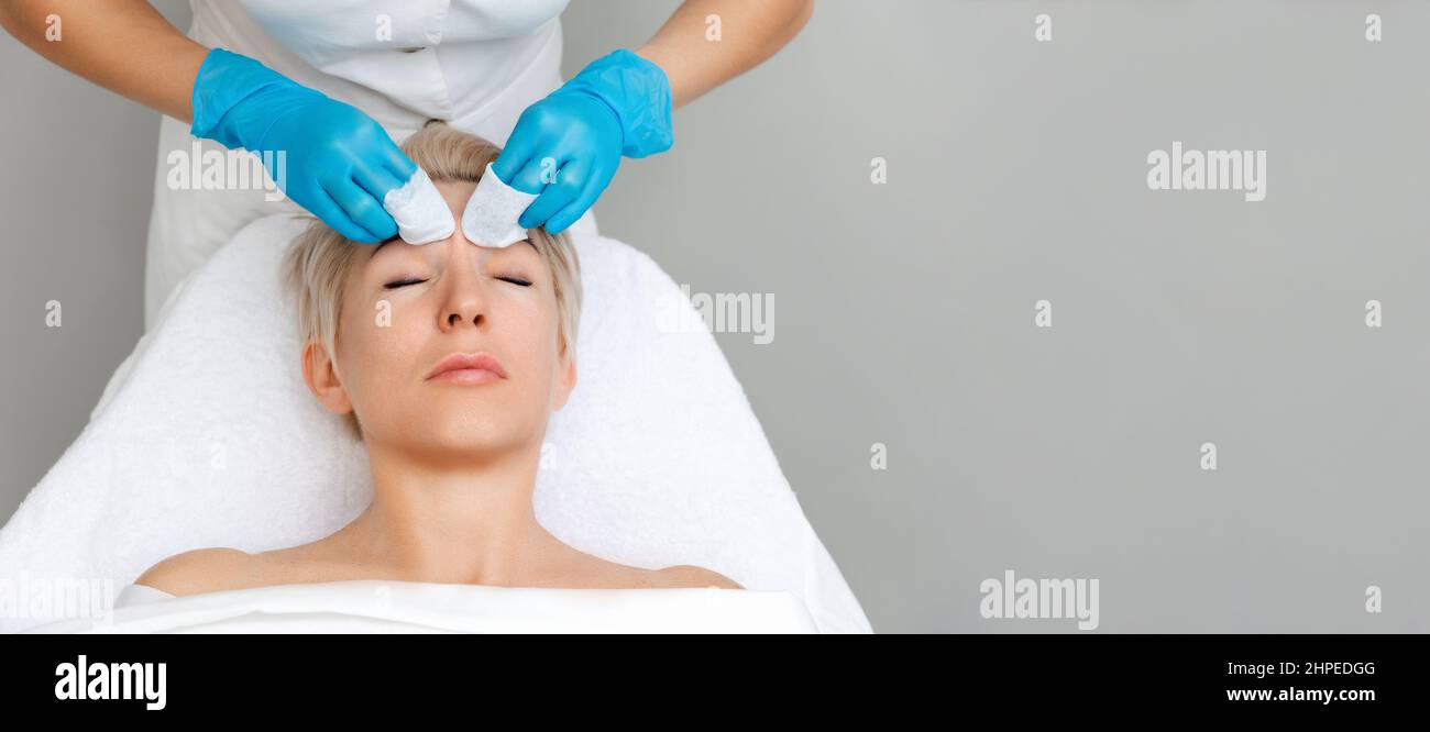 Professional cosmetologist does a deep mechanical cleaning forehead of ...
