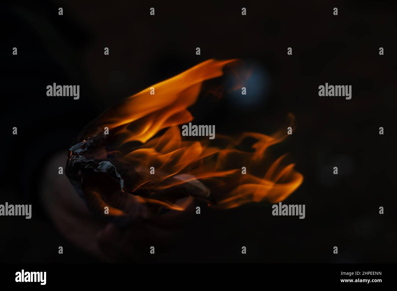 Close-up of a man's hand holding a burning sheet of paper. Sheet with ...