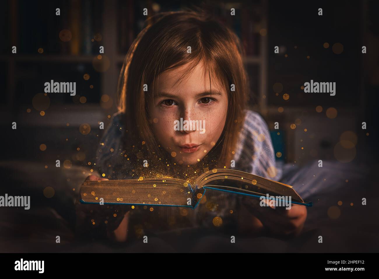 magic photo. a girl lying on the bed and blows gold dust off a book ...