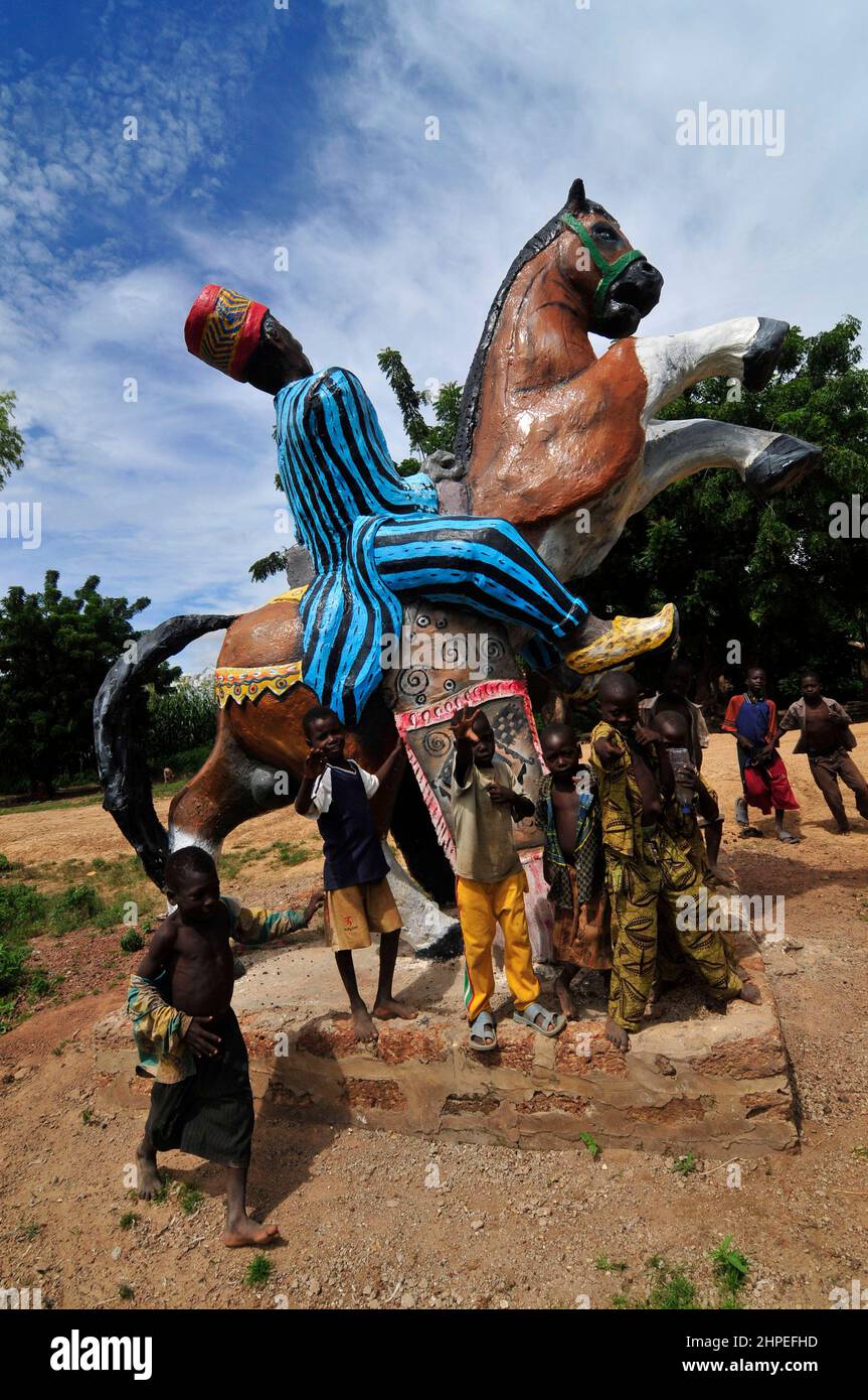 Mossi children playing by a statue of a Mossi chief riding his horse in ...
