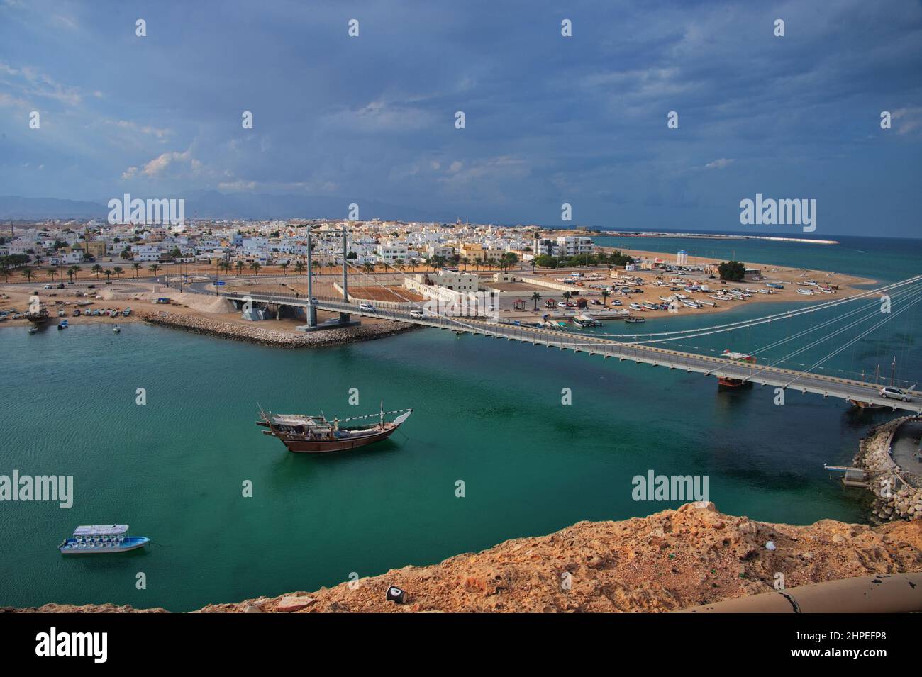 The bay of Sur in Oman with traditional wooden boats and with town in ...