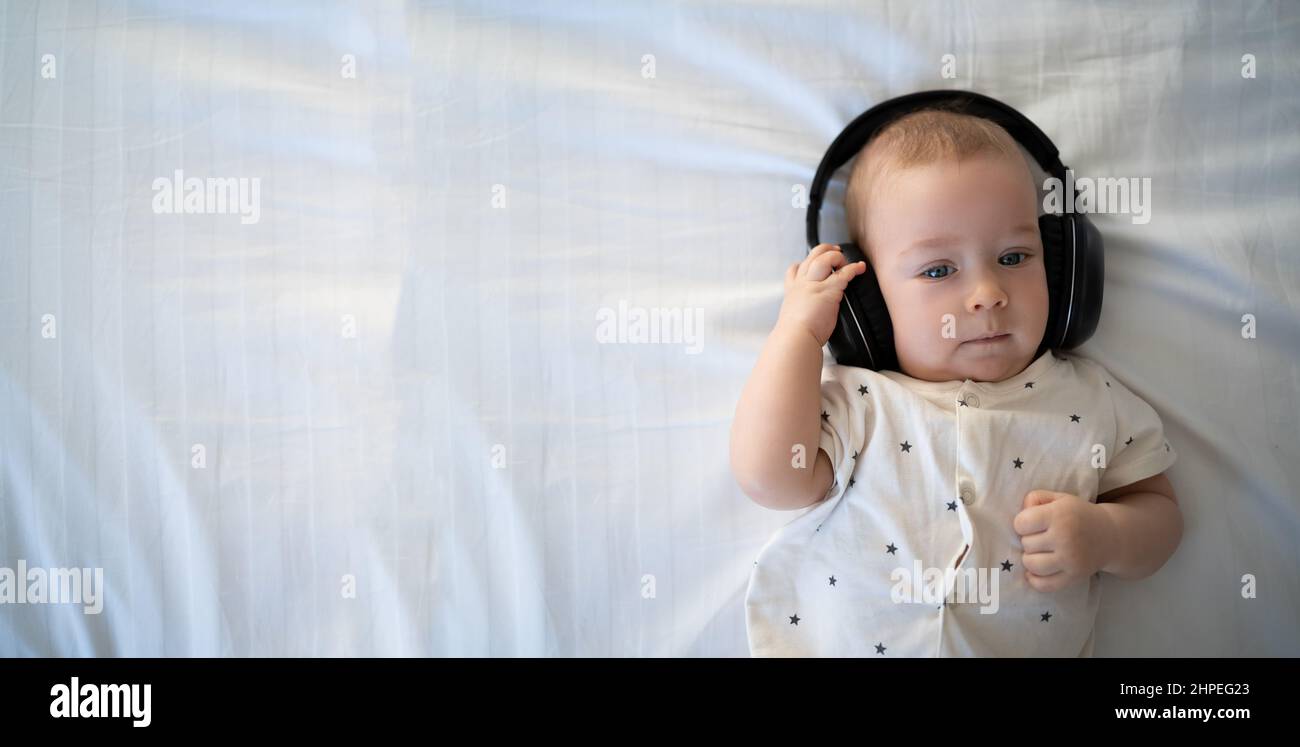 Pop music. Happy smiling newborn baby listening to music with ...