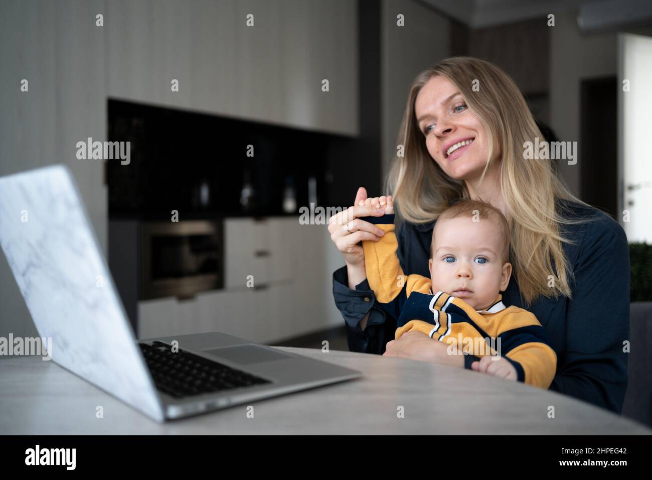 Mother woman with baby working remotely, video conference or zoom call ...