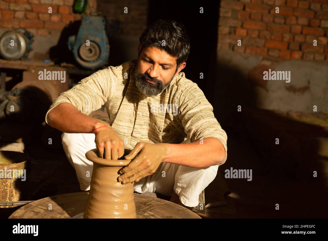 Indian male pottery maker building a clay pot, Beard man worker or ...